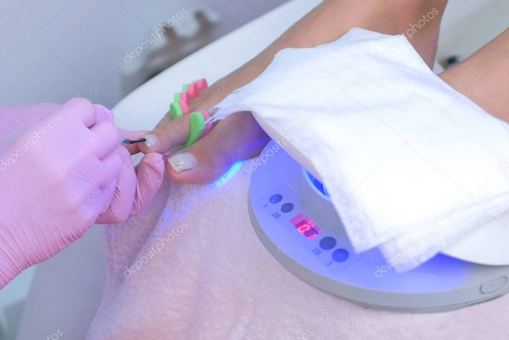 Maestro pedicurista está cubriendo pintar clientes dedos de los pies ...