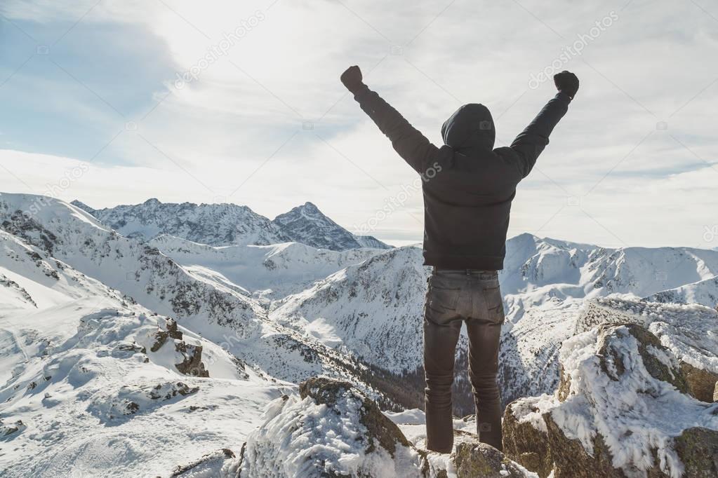 Happy man mountain climber raising hands on top of snowy mountains ...