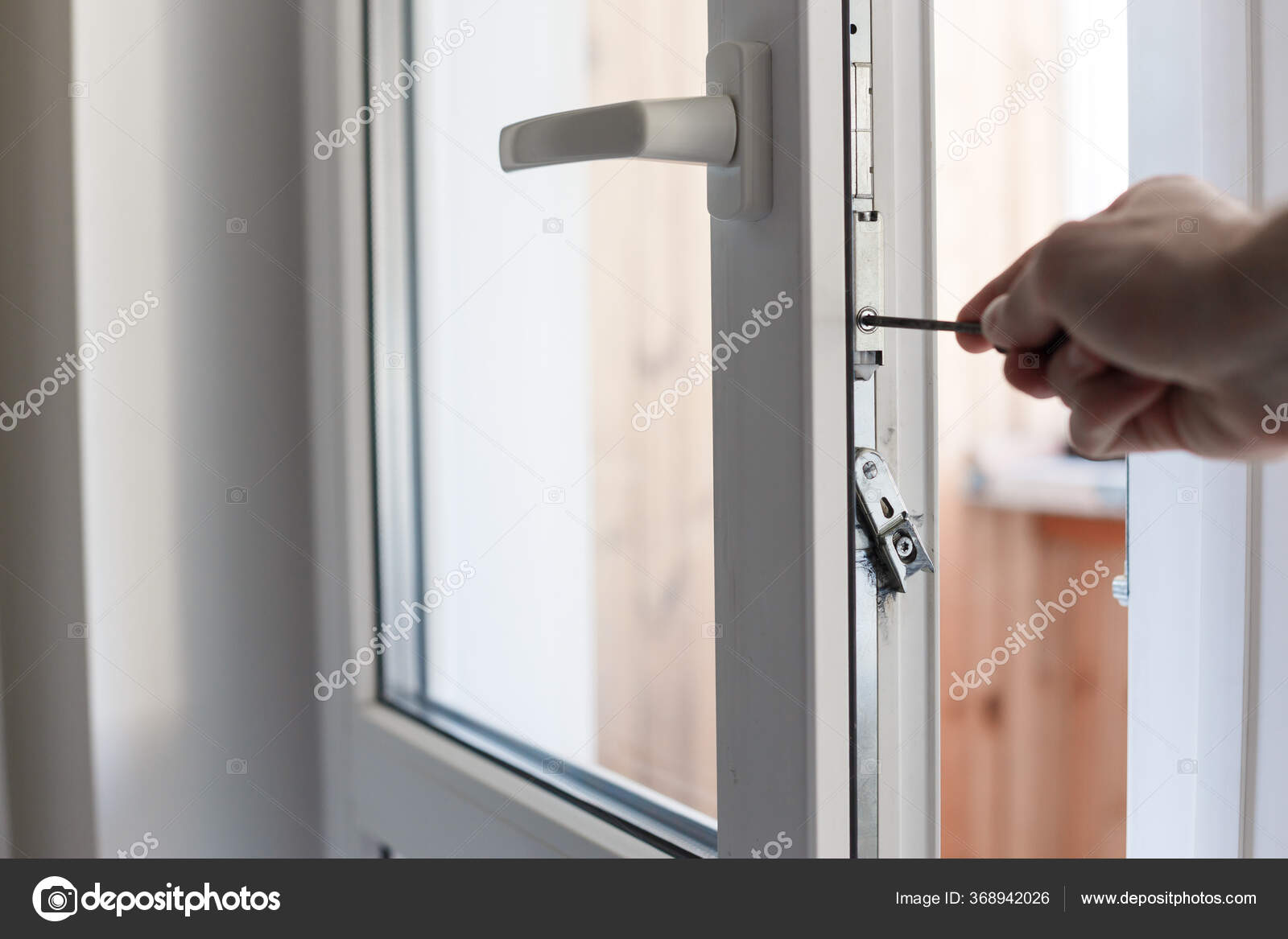 Mans hand uses screwdriver for adjustment of hardware of the uPVC door ...