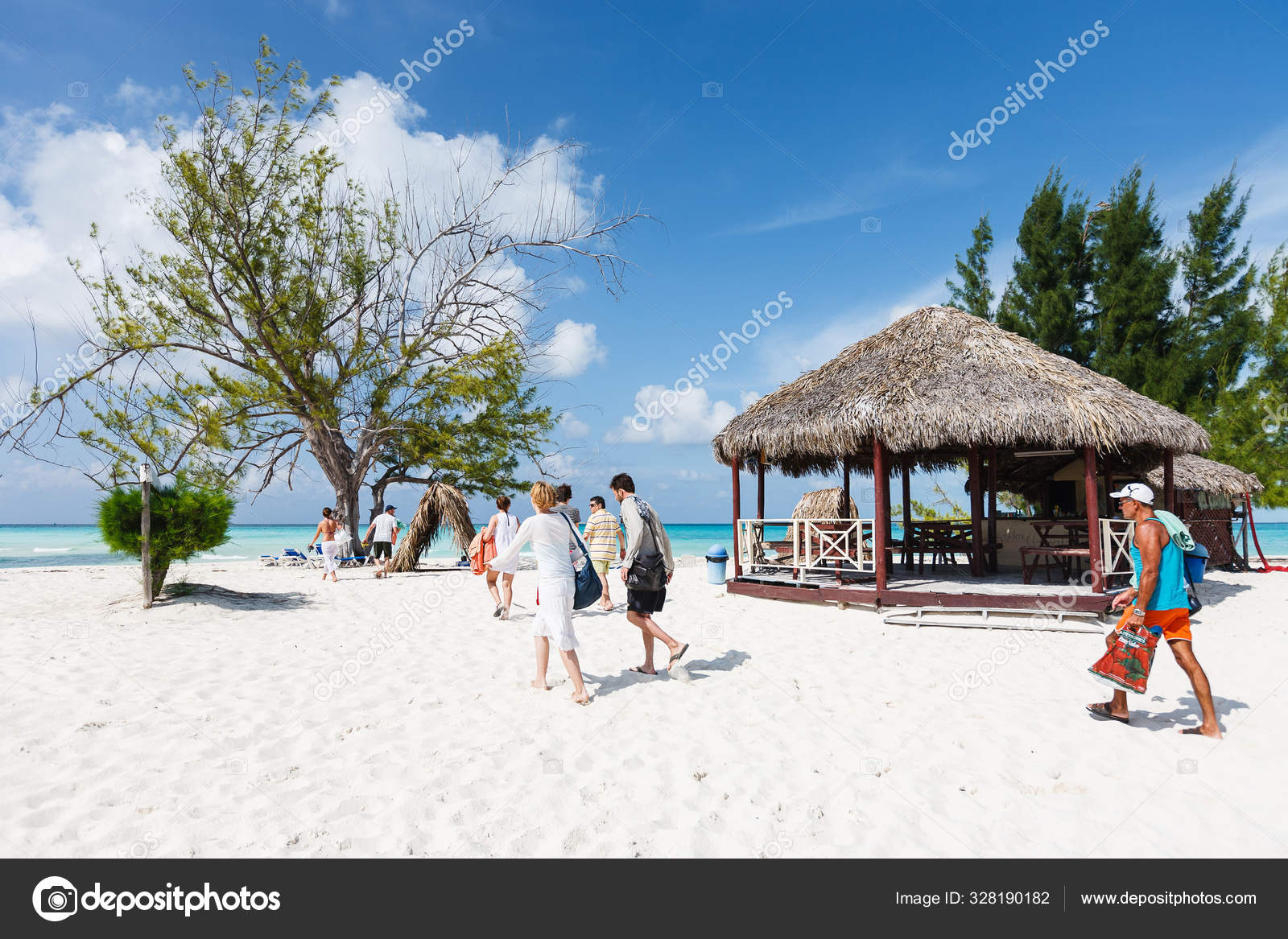 Group of tourists go to the dazzling beach to sunbathe, swim and relax ...