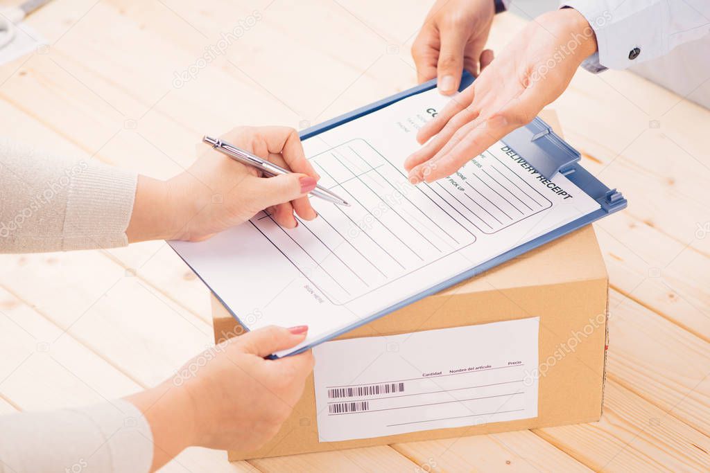 Mujer firmando recibo de cliente y recibiendo el paquete del repartidor ...