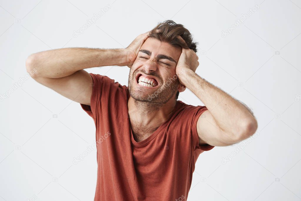 Emotional angry muscular man wearing red t-shirt closing eyes tight and ...