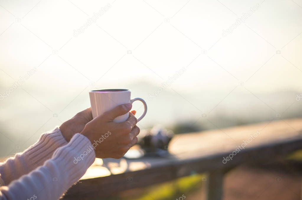 Woman drinking coffee in sun sitting outdoor in sunshine light enjoying ...