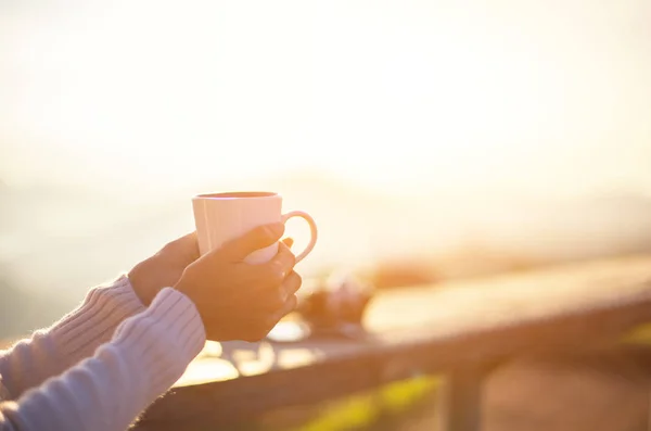 Woman drinking coffee in sun sitting outdoor in sunshine light enjoying ...