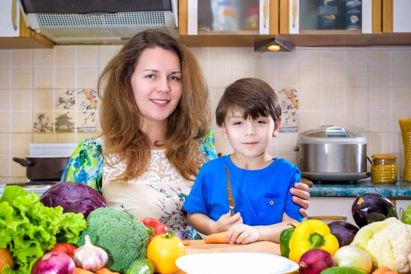 The young cook mother standing with her little son in the kitchen and ...