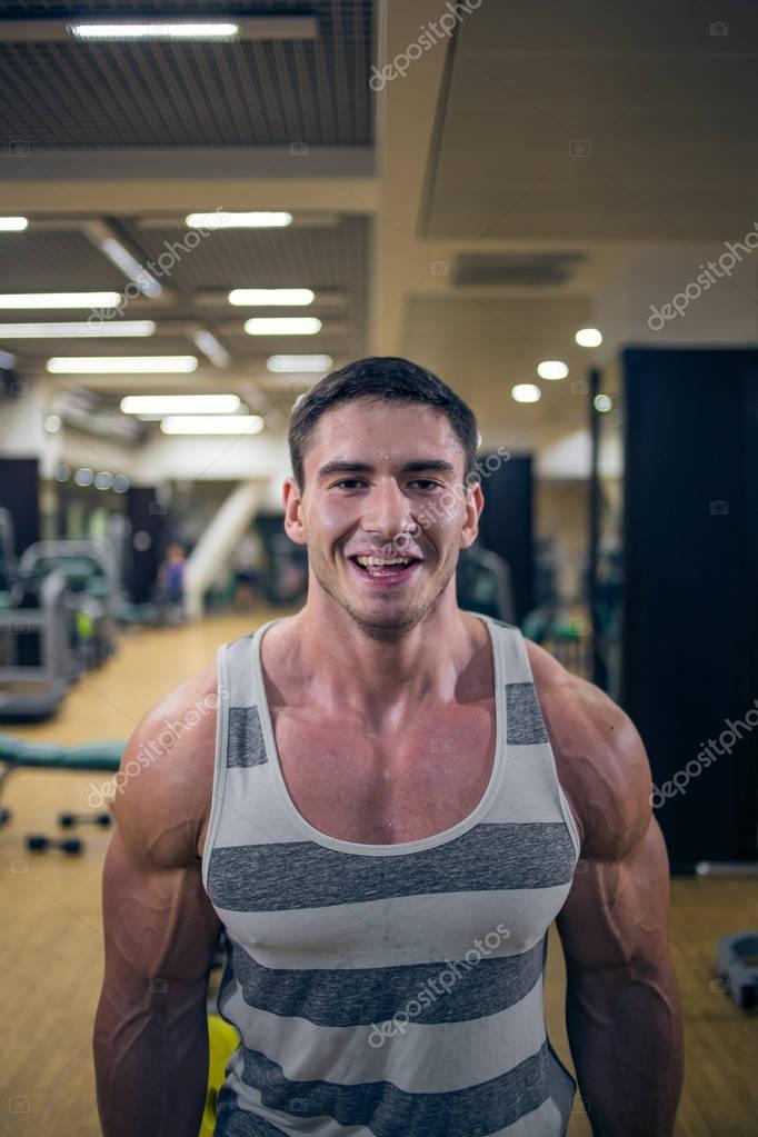 Cute bodybuilder sonríe y mira a la cámara. diversión en el gimnasio ...