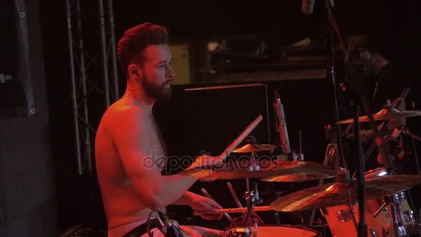 Drummer with a beard and a naked torso playing drums during a rock band ...