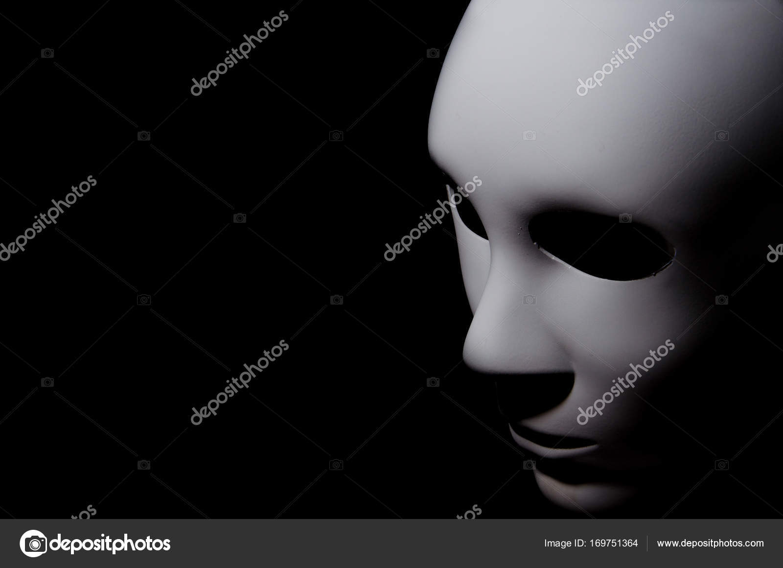 White mask with neutral expression and shadows on dark background ...