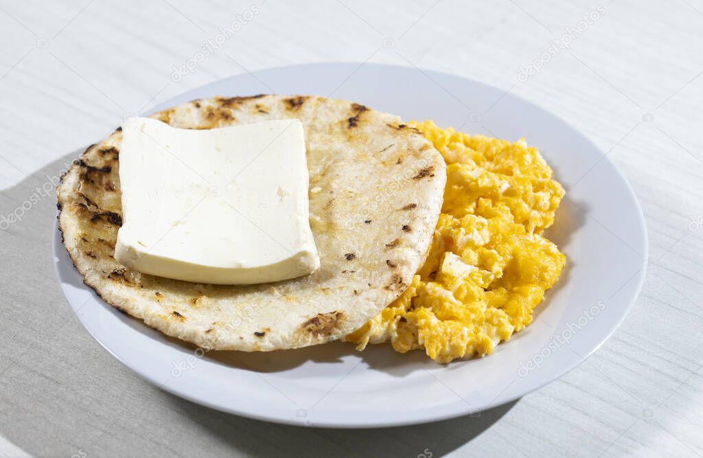 Desayuno arepa, queso y huevo revuelto, plato tradicional colombiano 2024