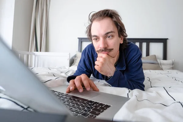 Man working at home lying on bed during quarantine, distance work ...