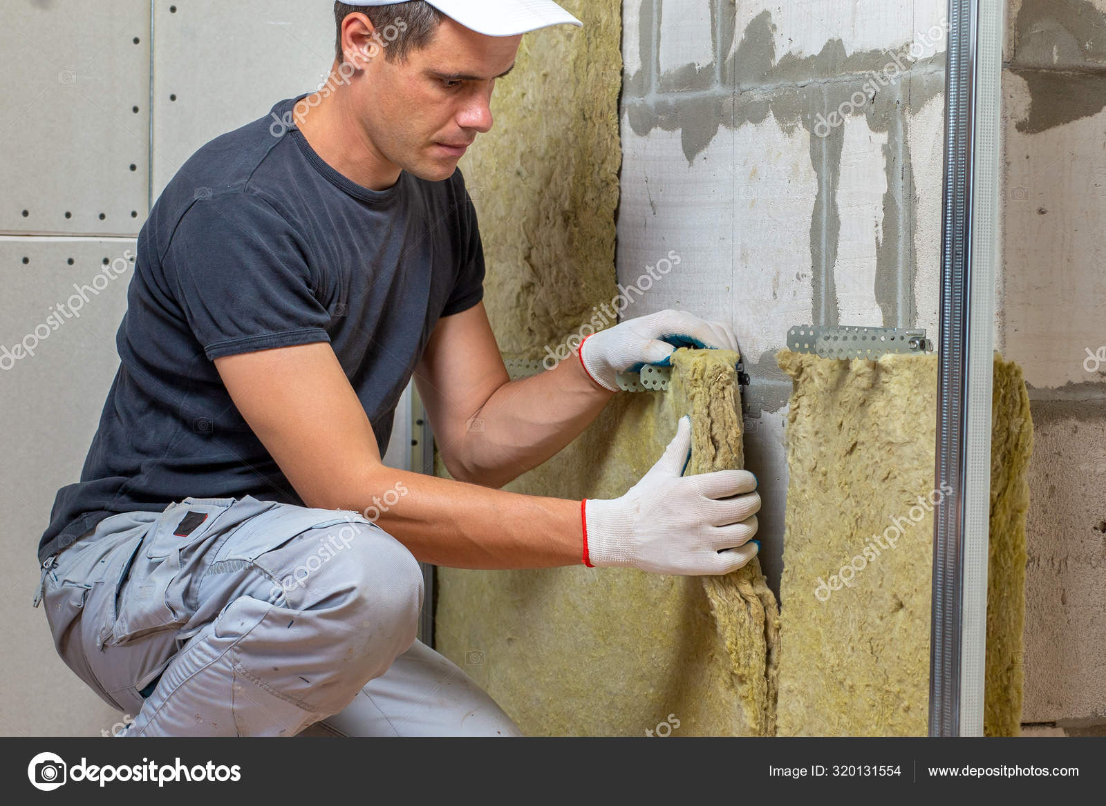 Worker insulating a room wall with mineral rock wool thermal ins ...