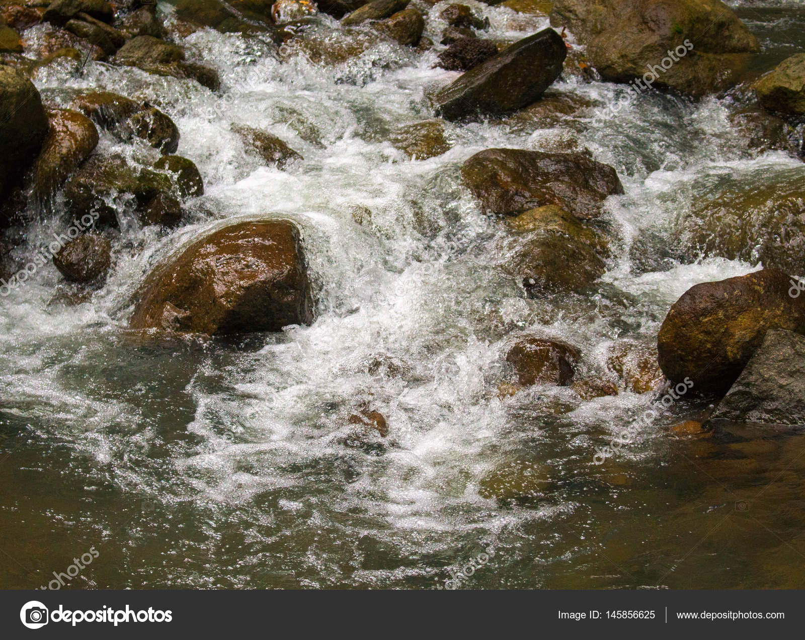 Fresh water river among black rocks. Fresh aqua fast stream in stones ...