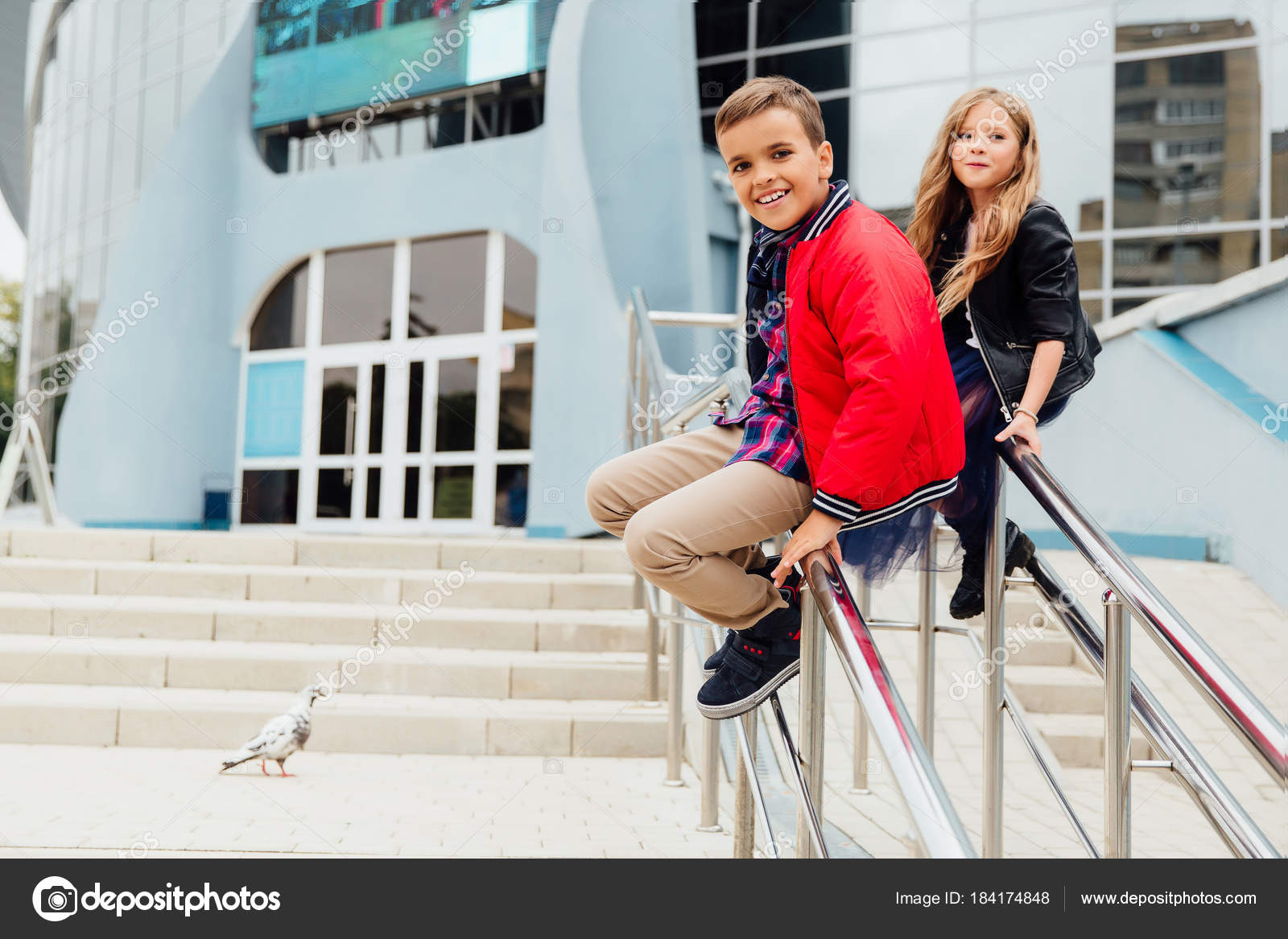Two kids: Beautiful Children play on the railing in the street on the ...