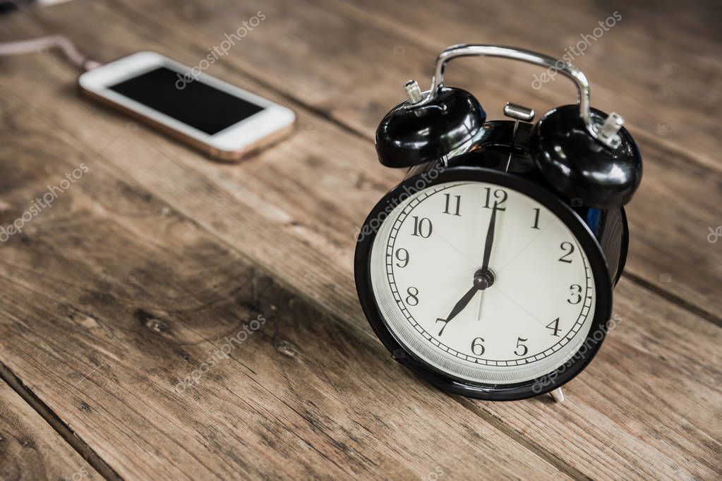 horas del reloj a las 7 de la mañana en la mesa de madera con la carga ...