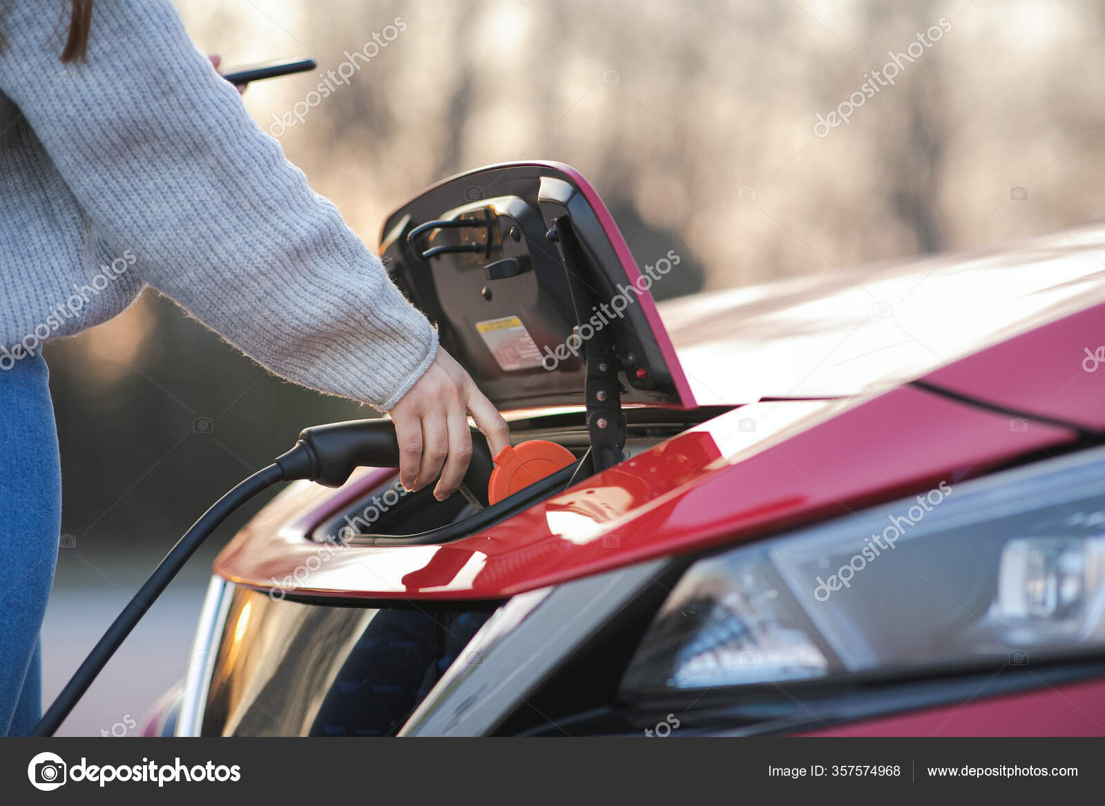 Woman is plugging electric vehicle for charging car battery at parking. Close up. Plugged ...