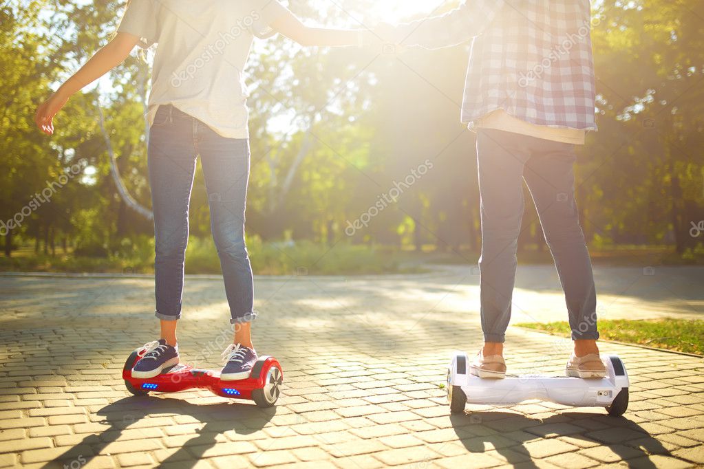 Young man and woman riding on the Hoverboard in the park. content ...