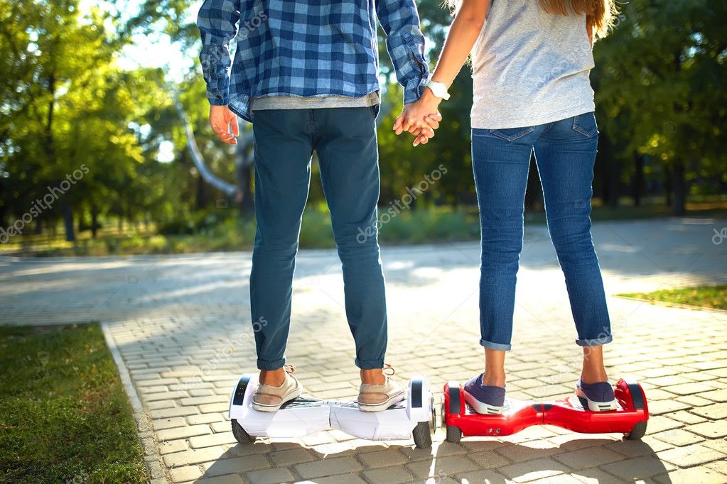 Young man and woman riding on the Hoverboard in the park. content ...
