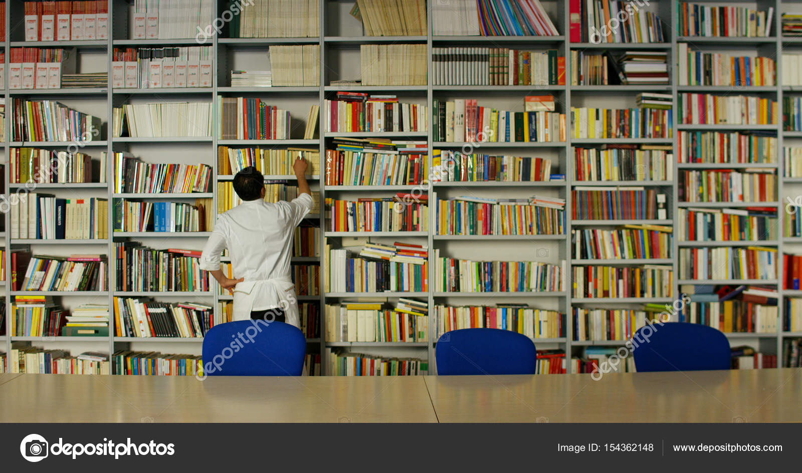 A young and beautiful doctor in a library smiling happy and holding ...