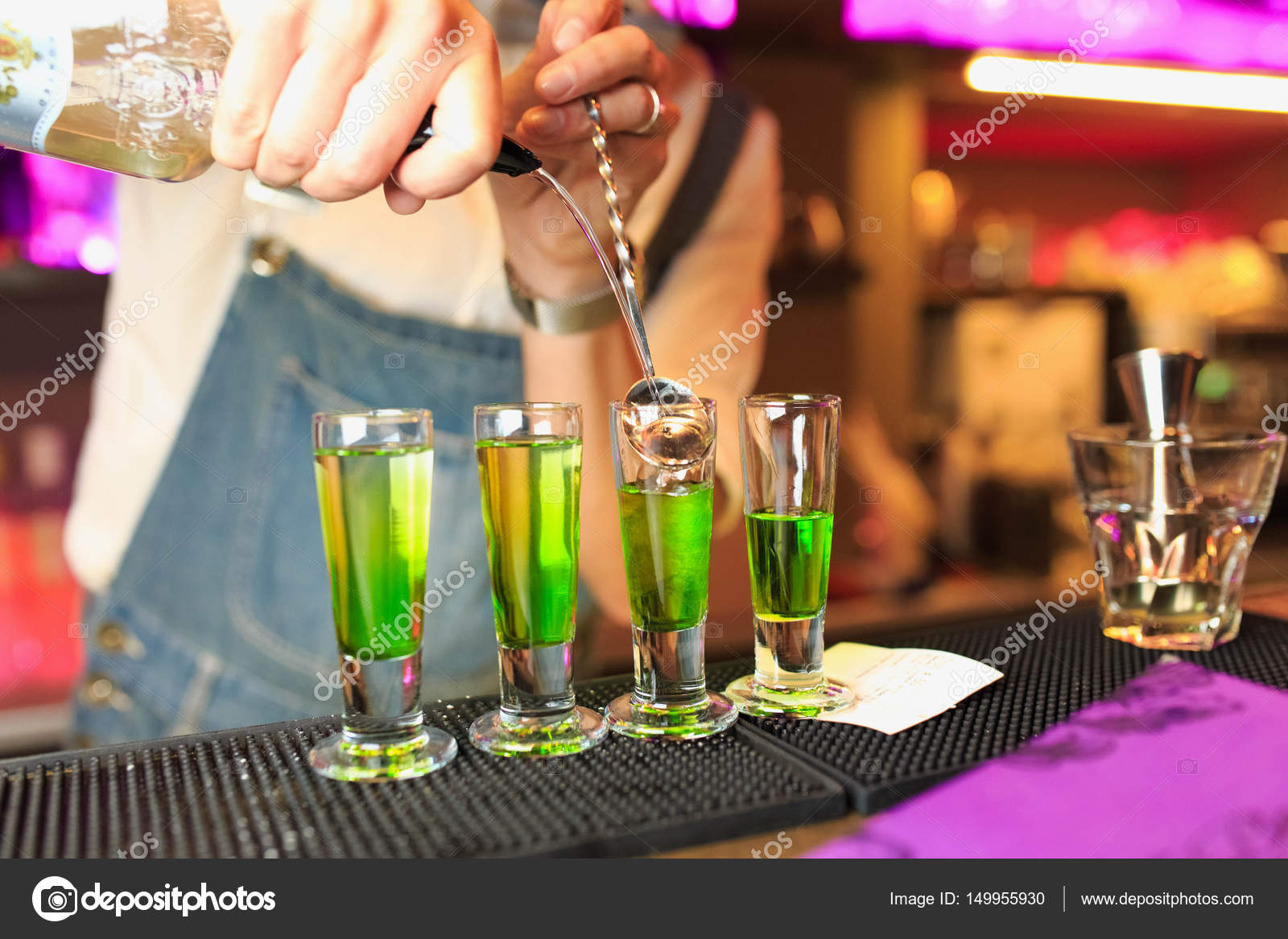 The barman's hands pouring absinthe into one of the stacks standing on ...