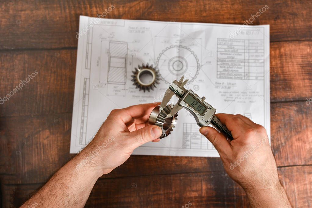 Un ingeniero de trabajo comprueba el tamaño de un engranaje biselado ...