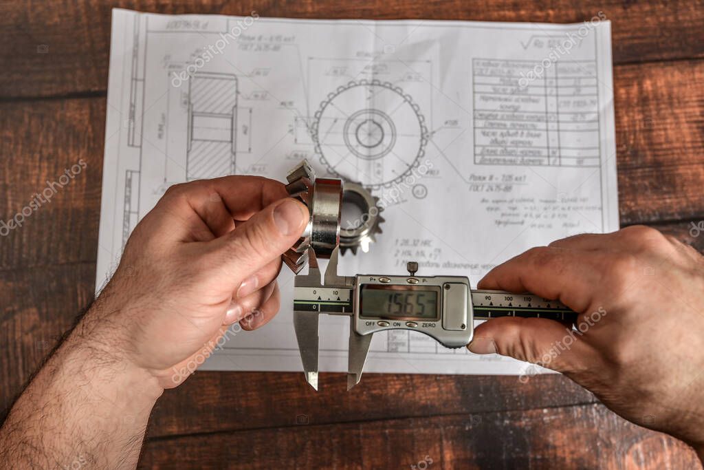 Un ingeniero de trabajo comprueba el tamaño de un engranaje biselado ...