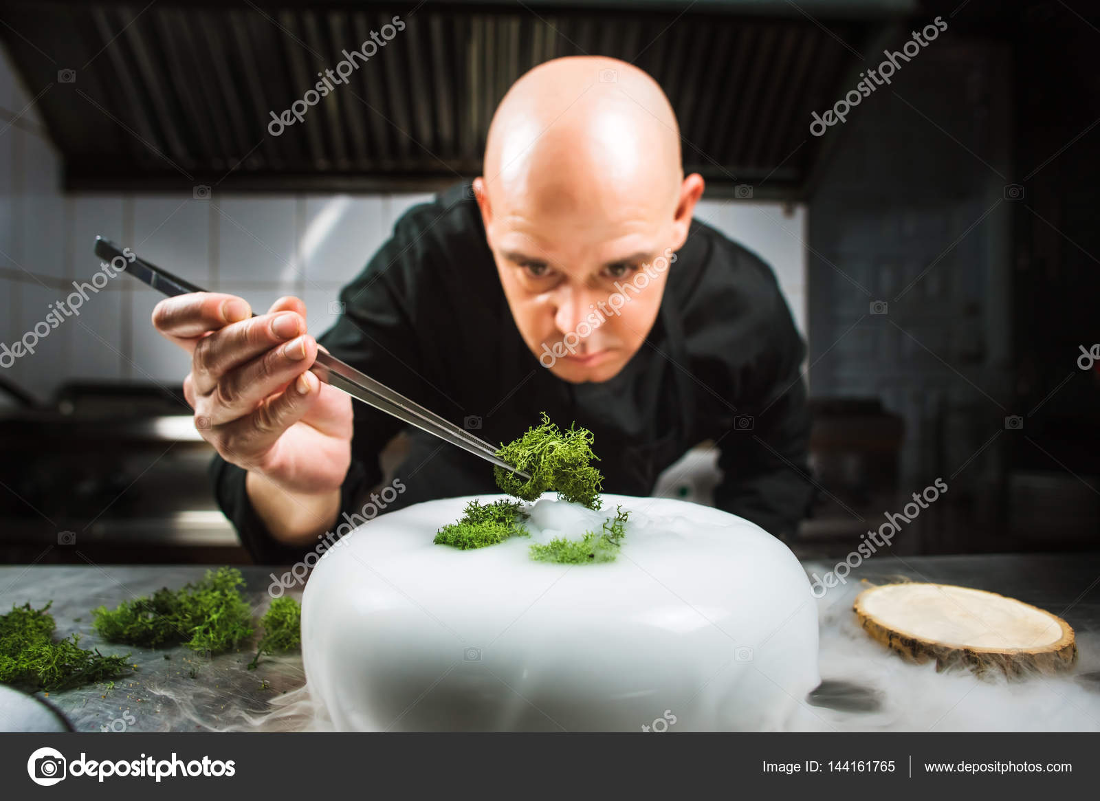 Chef is concentrated on preparing modern molecular dish with pincers ...