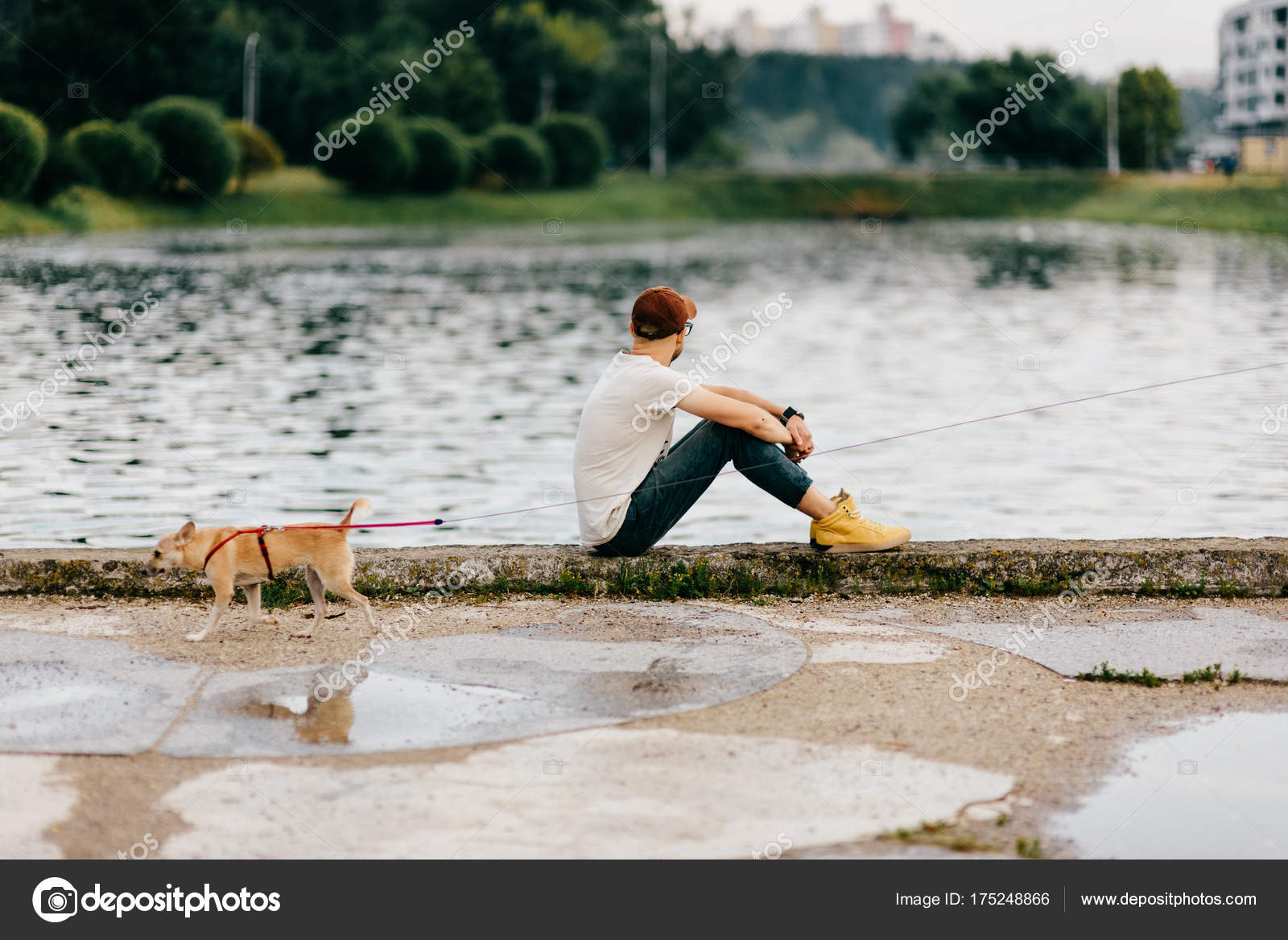 Barefoot lonely unknown adult man sitting on edge of embankment outdoor ...