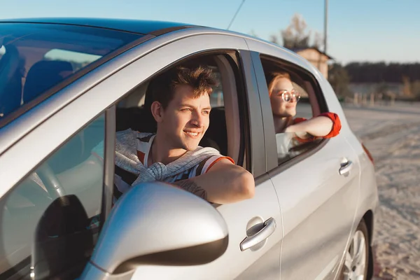 Pretty young couple driving the car at sea shore. Woman and man having ...