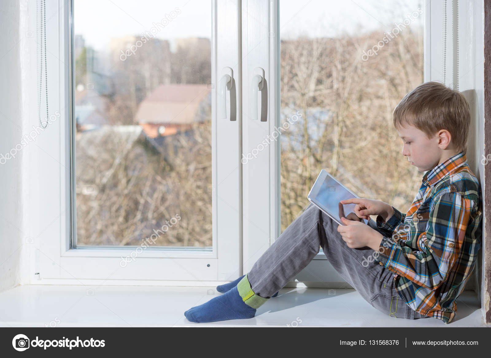 Boy sitting near window Stock Photo by ©upslim 131568376