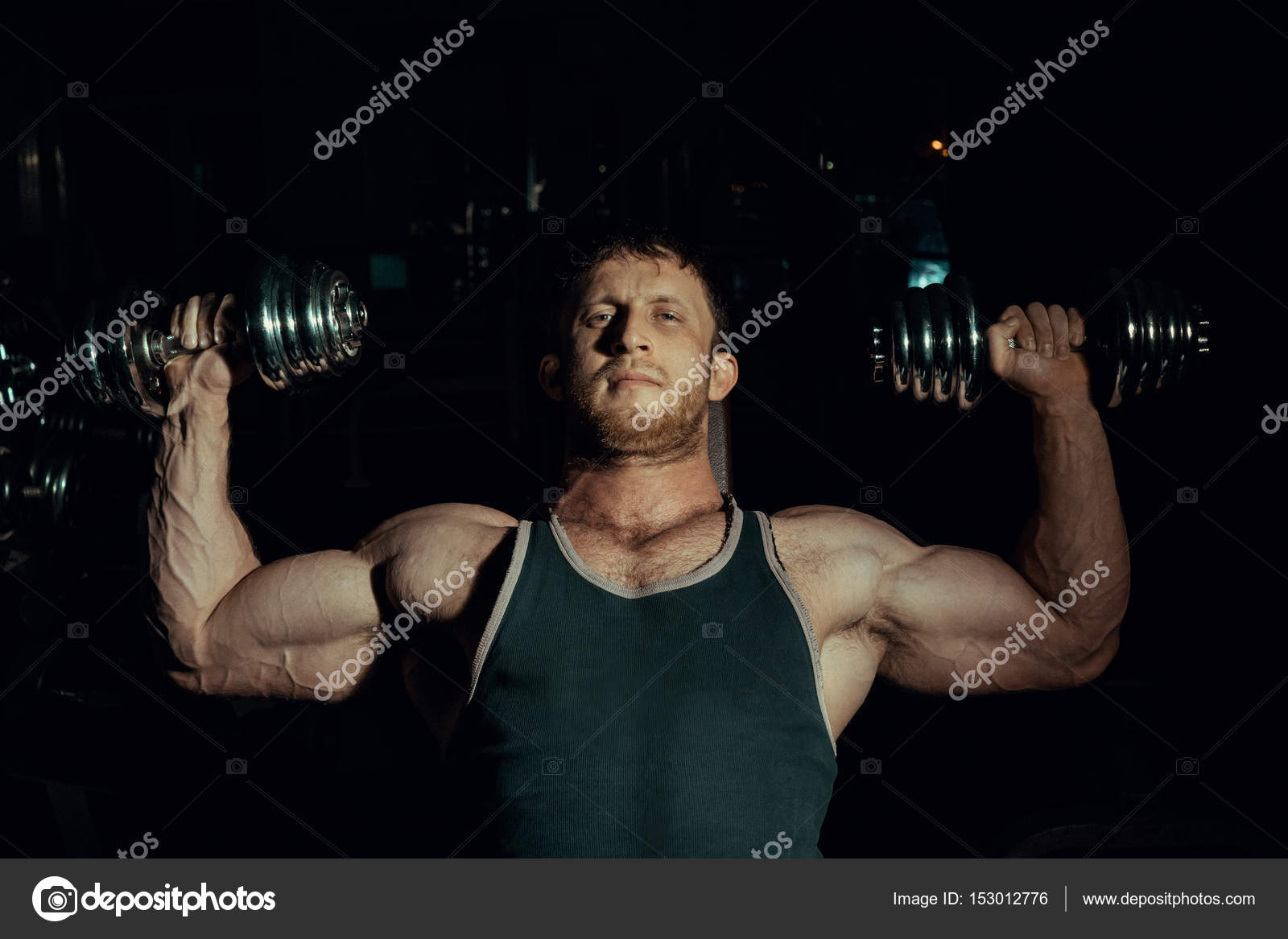 Hombre guapo con bíceps grandes haciendo ejercicios con pesas sobre un ...