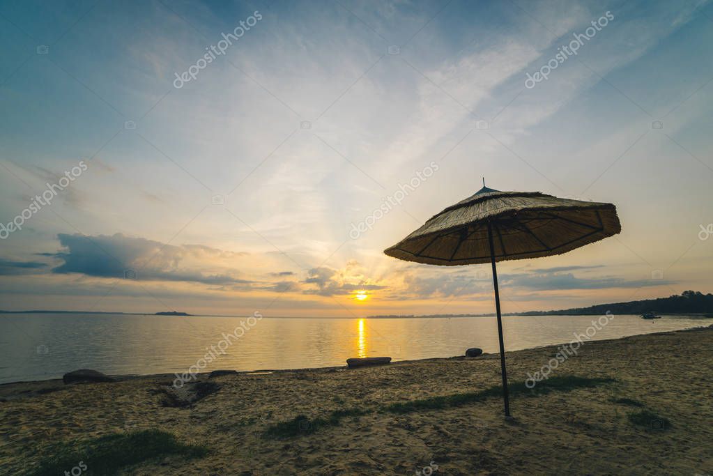 umbrellu playa en la playa con salida del sol en el fondo 2024