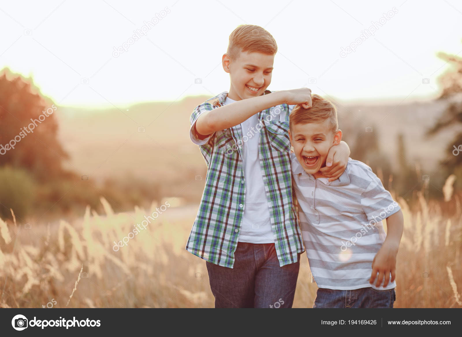 Brothers having fun in a field Stock Photo by ©hetmanstock 194169426