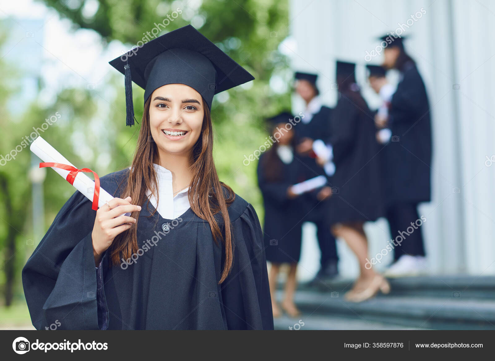 A young female graduate against the background of university graduates ...