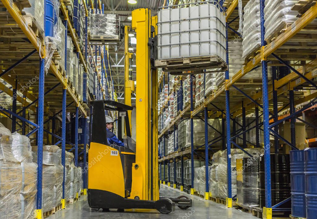 Trabajador de almacén en apilador cargando carga en estante 2024