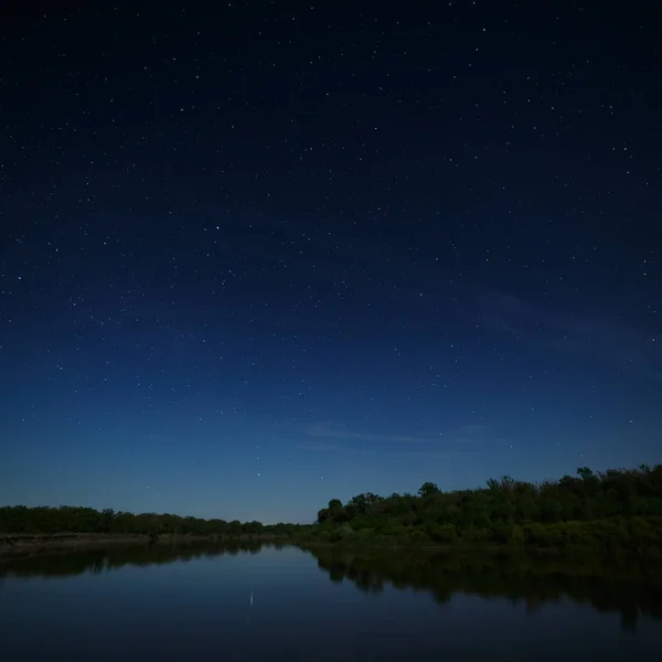The stars in the night sky are reflected in the river. The lands ...