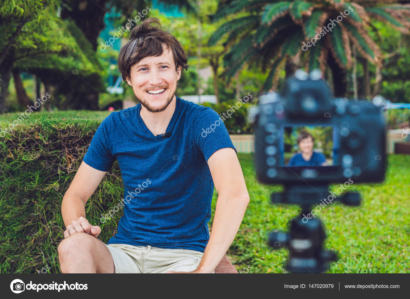 Young man blogger records video in front of the camera in the park ...