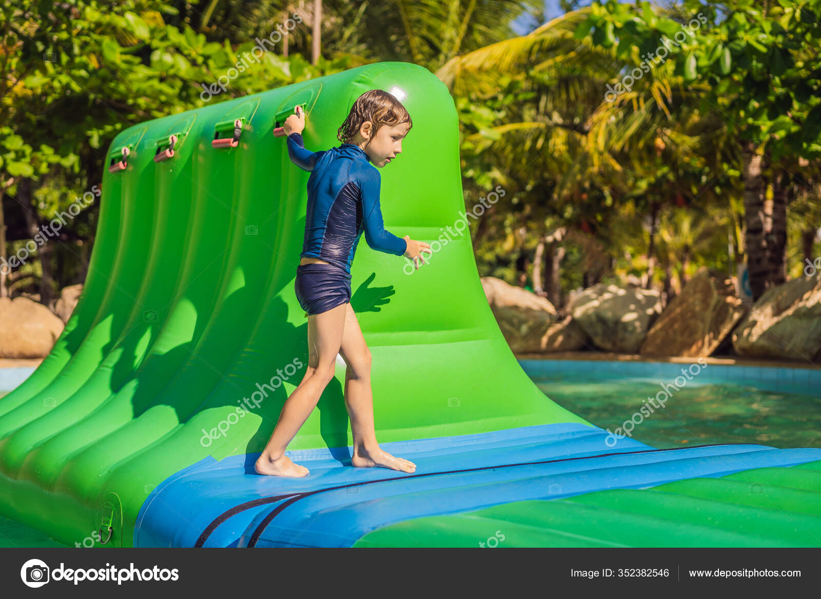 Cute boy runs an inflatable obstacle course in the pool Stock Photo by ...