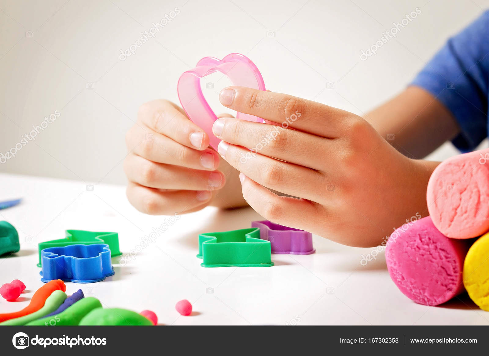 Child hands playing with modeling clay or plasticine on white table ...