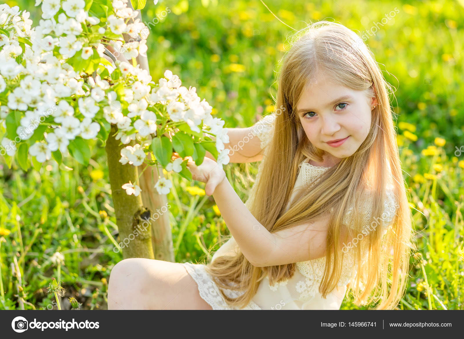 A beautiful little girl runs through a flowering garden in the s ...