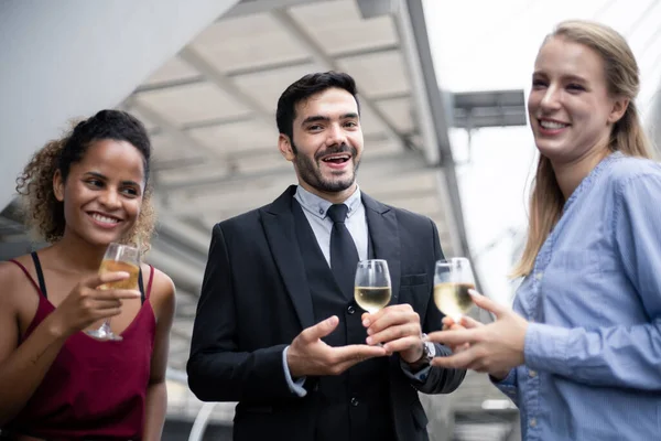 Business people clink glasses and drink wine to celebrate the ...