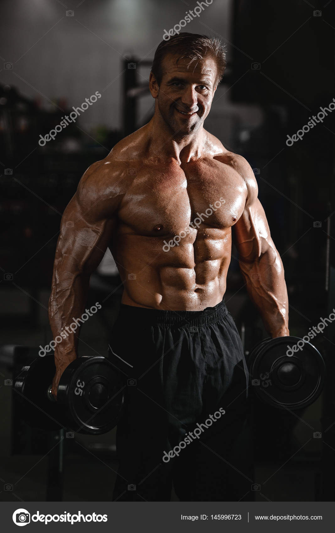Brutal strong bodybuilder man pumping up muscles and train gym Stock ...