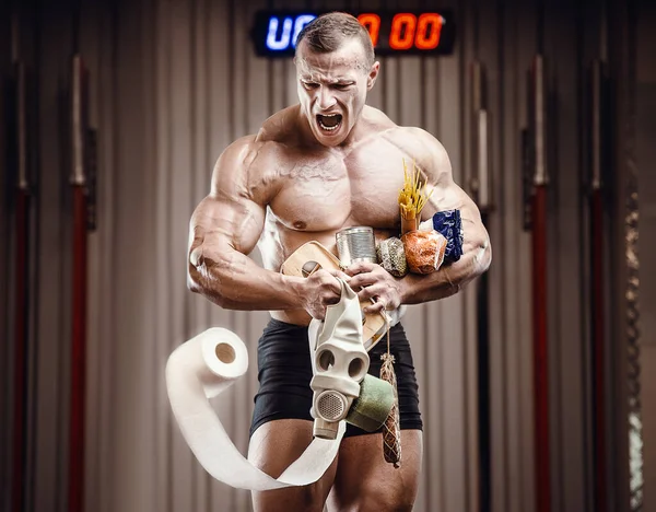 Bodybuilder athlete with axe, food in gas mask in gym. Muscle man with ...