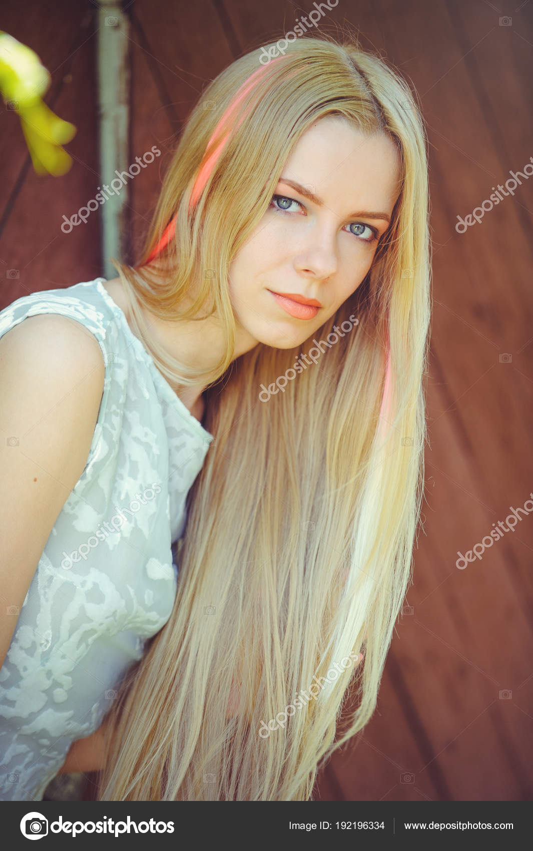 Attractive modest young blond woman on red wooden background her hair ...