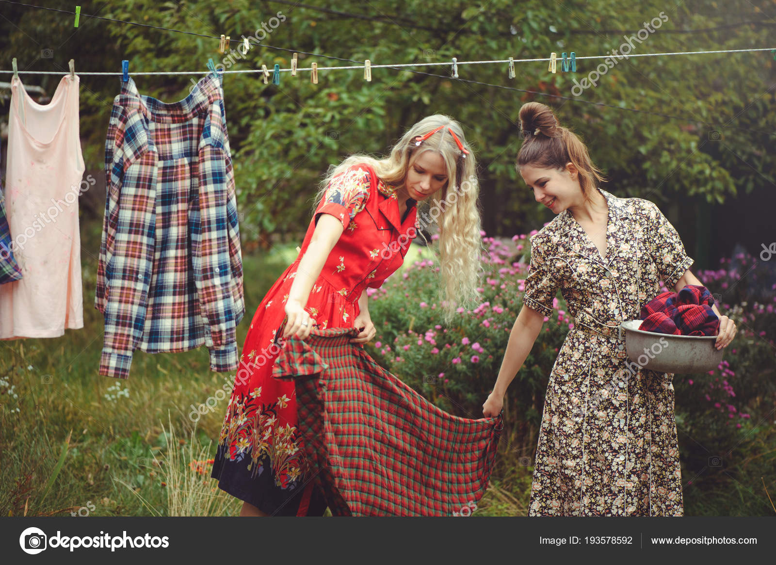 Mujeres jóvenes colgando ropa después de lavarse en el patio en th ...