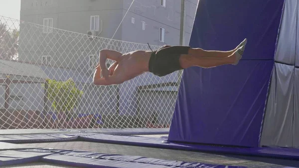 Professional gymnast jumping on the trampoline and doing tricks in air ...
