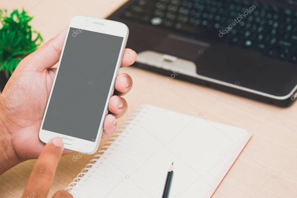 Businessman's hands holding and use mobile phone on on office table ...