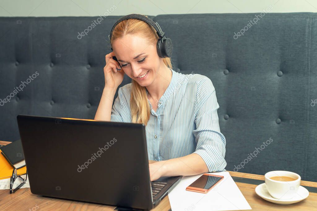 sonriente mujer joven con auriculares y est sentado frente a un ordenador port til abierto en ...