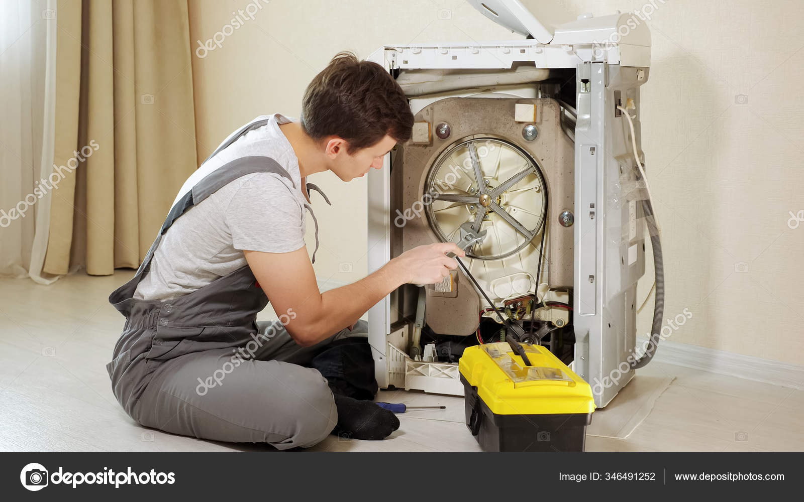 Master opens back panel of broken washing machine near wall Stock Photo ...