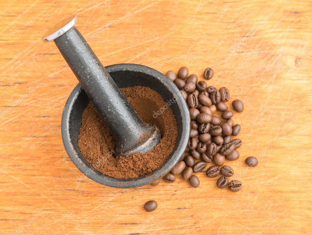 Granos de café triturados en un mortero de hierro fundido 2023