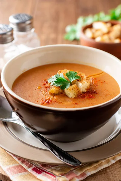 Red lentil cream soup with croutons in bowl on wooden table. Selective ...